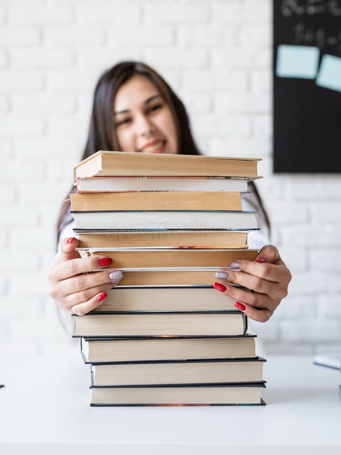 Young Teacher Sitting with Pile of Books Looking Away Ready for Lesson ...