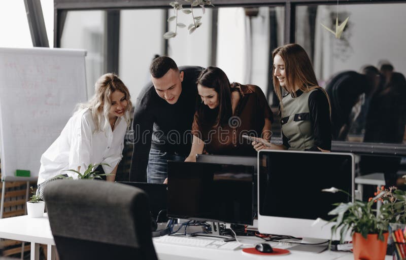 Young Team Works at the Desks with a Computer and Laptops in a Light ...