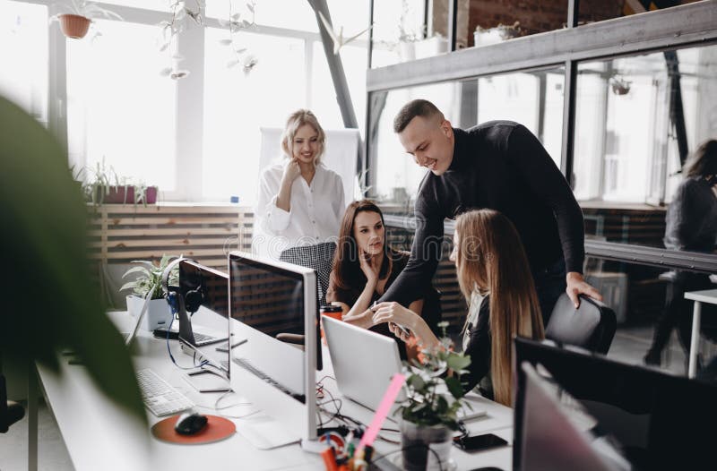 Young Team Works at a Desks with a Computer and Laptops in a Light ...