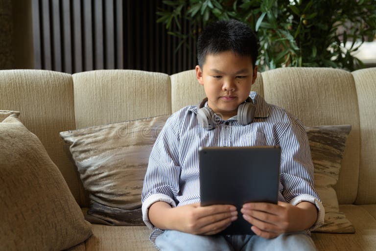 Thai Boy Using Digital Tablet Computer at Cafe with Headphones Stock ...