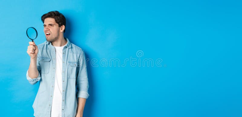 Young Thoughtful Guy Looking through Magnifying Glass, Reading ...