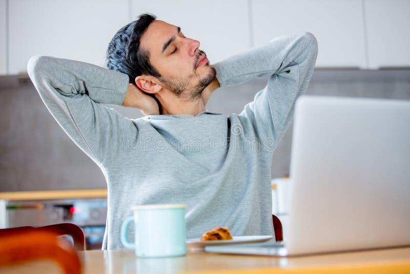 Young Tired Man Sitting at Table with Claptop Computer Stock Photo ...