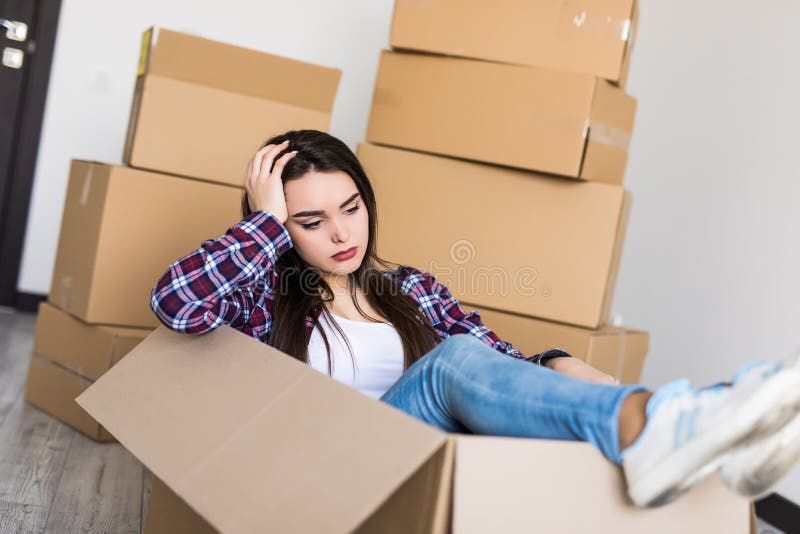 Young Tired Woman Sitting Inside a Box among a Stack of Moving Boxes ...