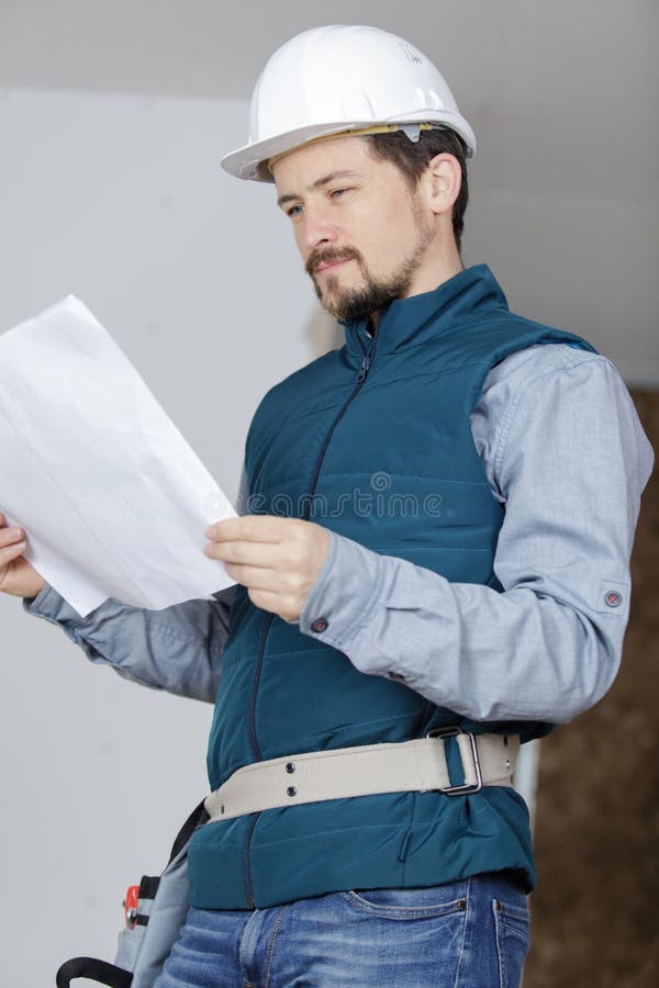 Young Tradesman Looking at Paperwork Stock Image - Image of engineering ...