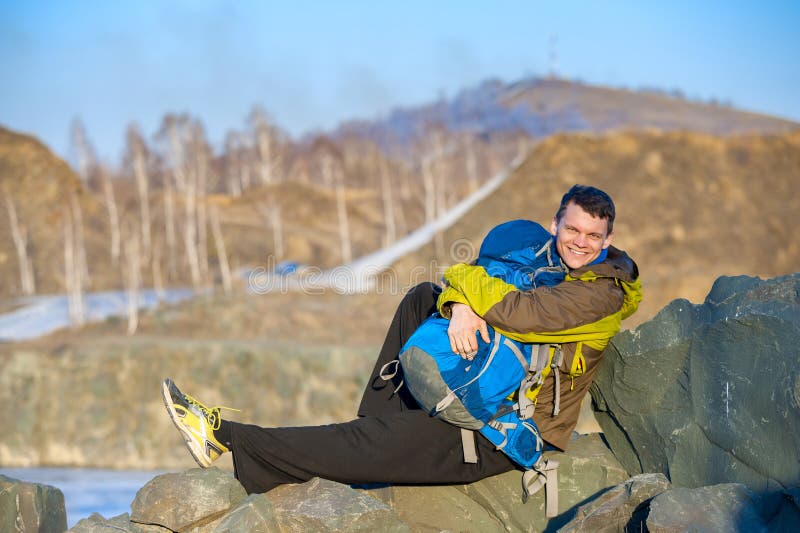 Young Traveler Sitting on the Rocks with a Backpack and Smiling Stock ...