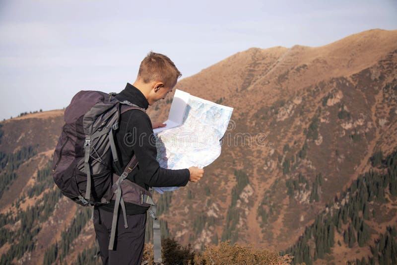 Young Traveller with Backpack Checks Map To Find Direction in Mountains ...