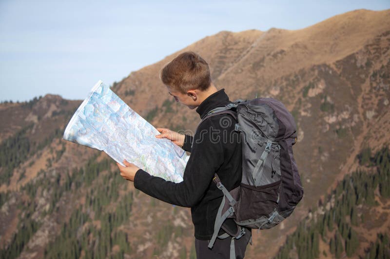 Young Traveller with Backpack Checks Map To Find Direction in Mountains ...