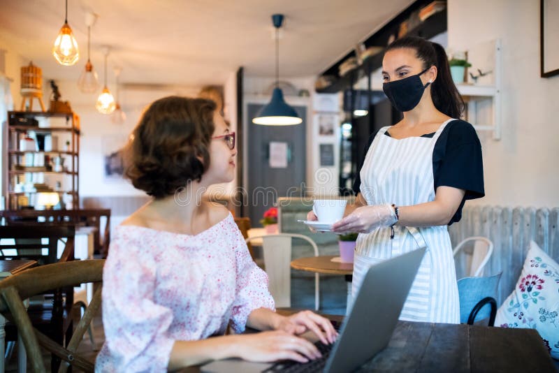 Young Waitress with Face Mask Working Indoors in Cafe, Serving Customer ...