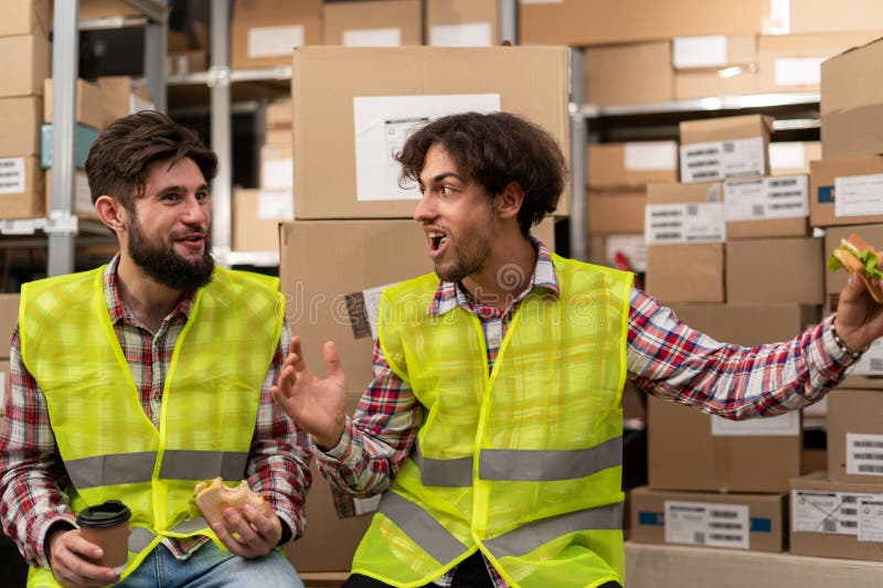 Young Warehouse Workers Have Lunch and Talk during a Break while ...