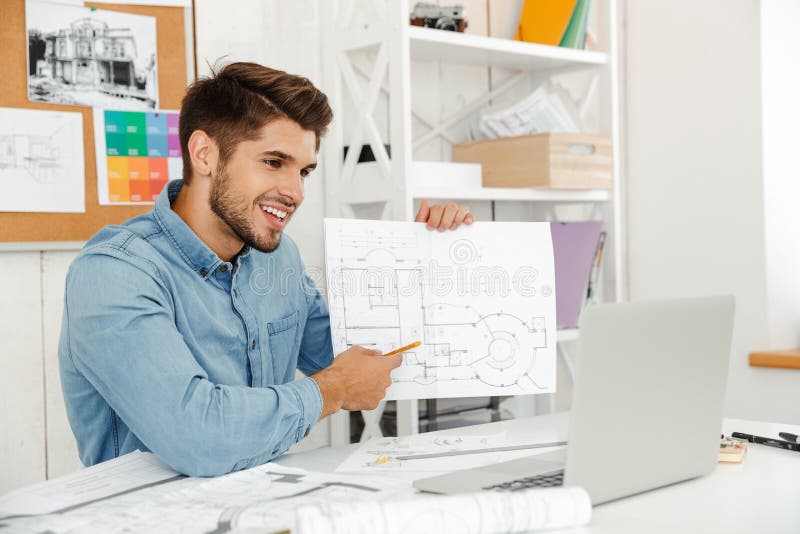 Young White Man Smiling while Working with Laptop and Drawings in ...
