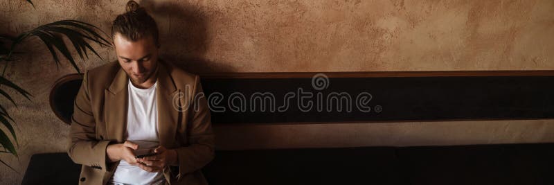 Young Man Using Mobile Phone while Working with Laptop in Cafe Stock ...