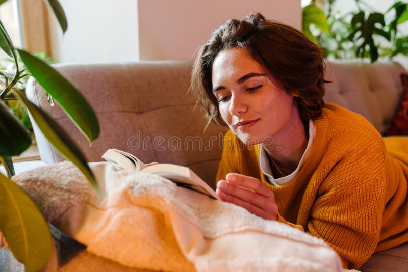 Young White Woman Reading Book while Lying on Couch Stock Image - Image ...