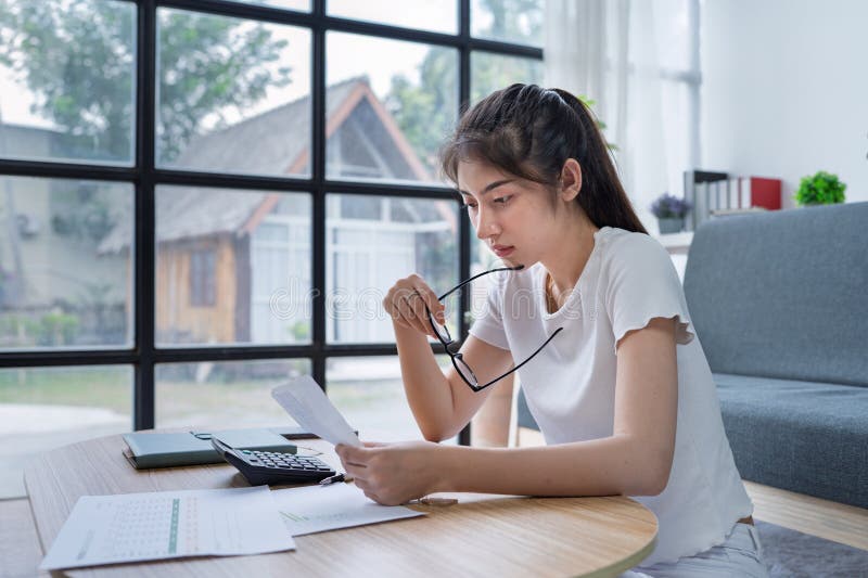 Young Woman Analyzing Receipt and Financial Documents at Home Office ...