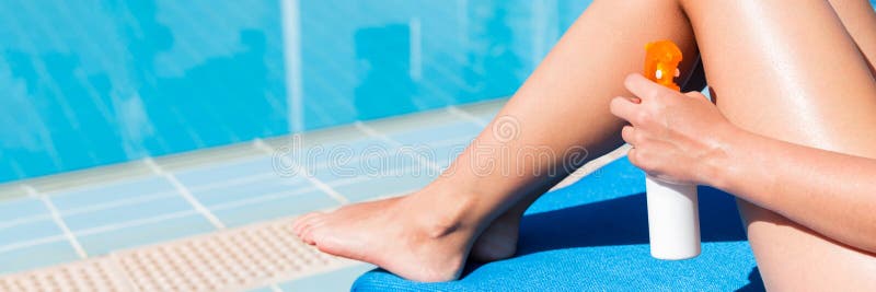 Young Woman Is Applying Sun Cream On Her Smooth Tanned Legs By The Pool
