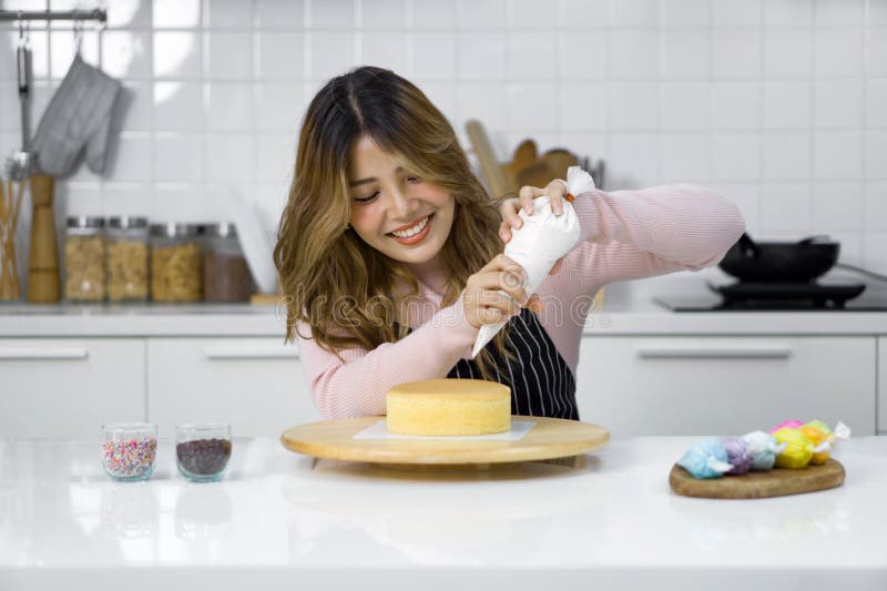 Young Woman in an Apron Using a Piping Bag, Pipe the Icing Onto the ...