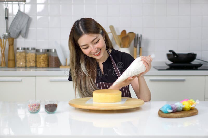 Young Woman in an Apron Using a Piping Bag, Pipe the Icing Onto the ...
