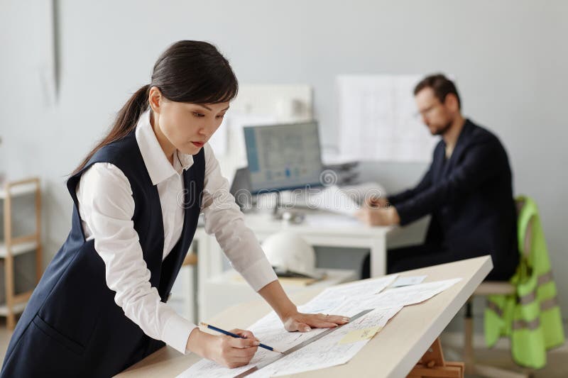 Young Woman As Engineer Drawing Blueprints and Plans at Table in Office ...