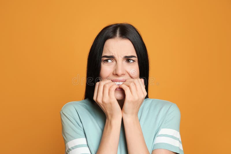 Young Woman Biting Her Nails on Yellow Background Stock Image - Image ...