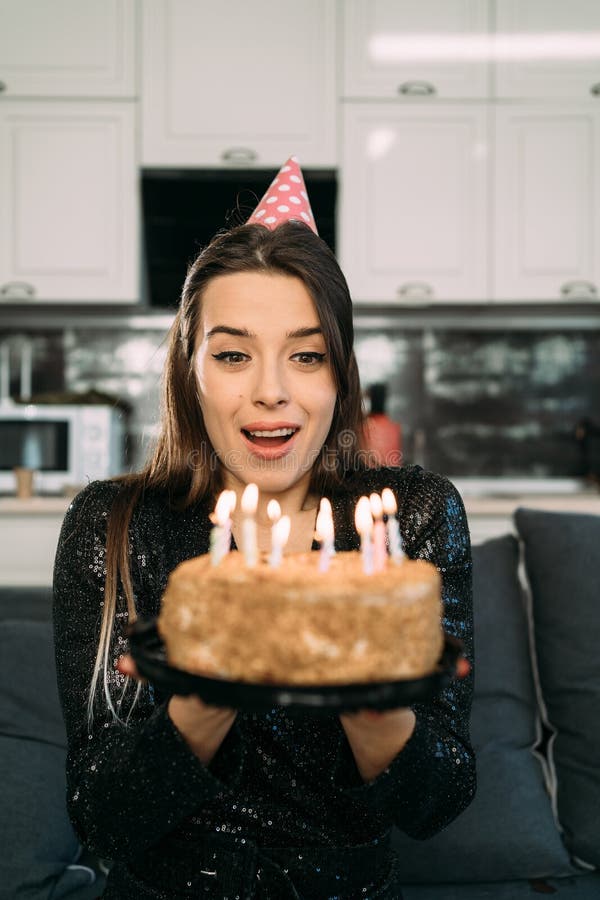 Young Woman Blowing Out Candles On A Birthday Cake A Girl Alone In A