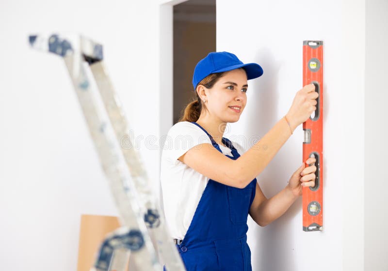Satisfied Young Woman Builder Checking Vertical of Walls with Level ...
