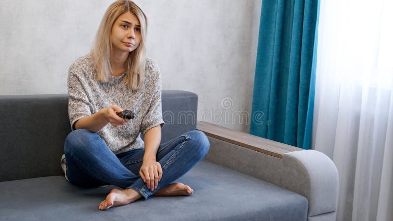 Young Woman Changing TV Channels with Remote Control Sitting on Sofa ... Young Woman Changing TV Channels with Remote Control Sitting on Sofa ...