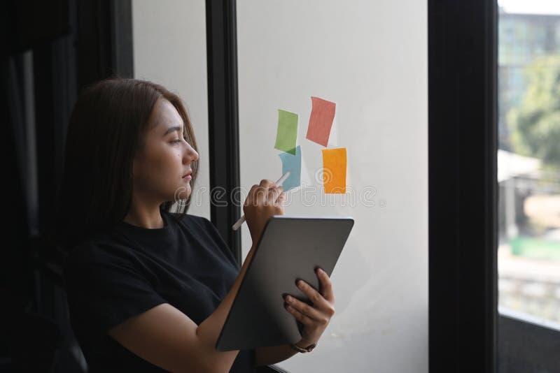 Young Woman Designer Holding Digital Tablet and Writing on Sticky Notes ...