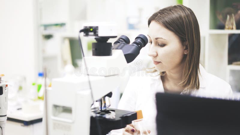 A Young Woman Doctor is Sitting in Front of the Microscope Stock Image ...