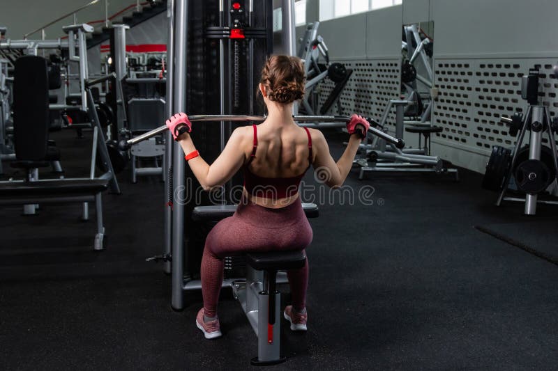 Young Woman Doing Exercises on a Pull-down Machine in the Gym. Body and ...