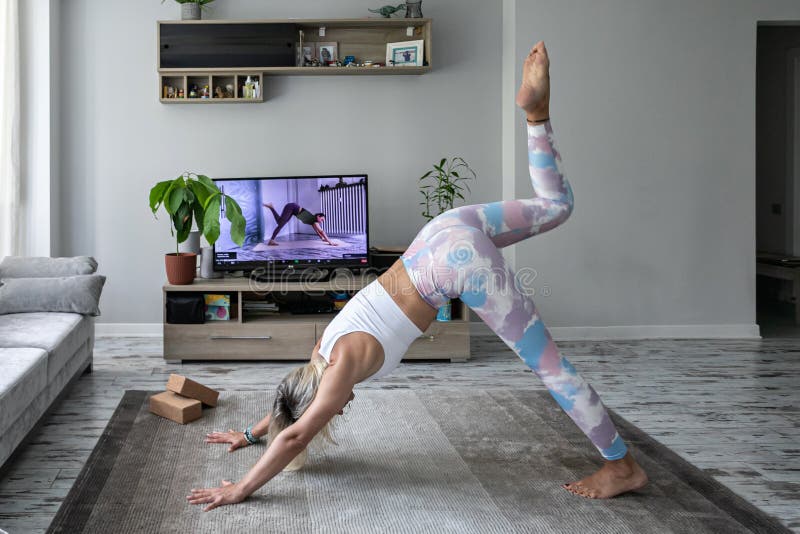 Young Woman Doing Online Yoga Exercise At Home Watching Tutorial On Tv