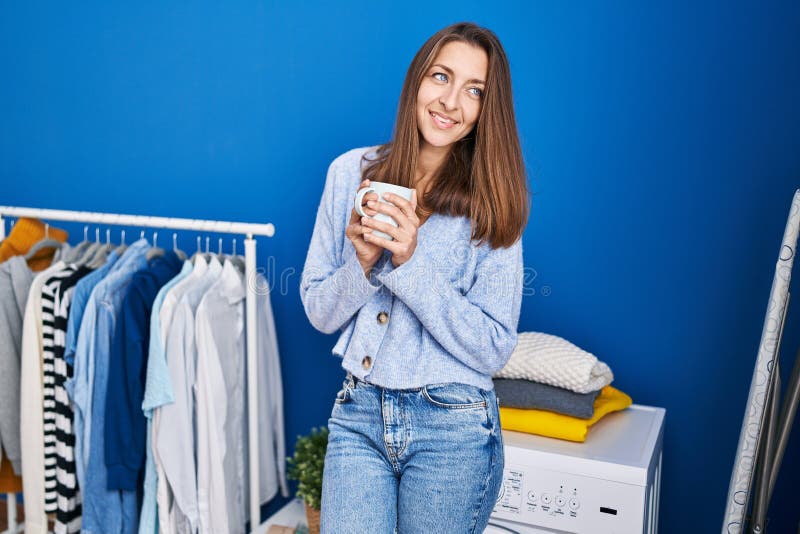 Young Woman Drinking Coffee Waiting for Washing Machine at Laundry Room ...