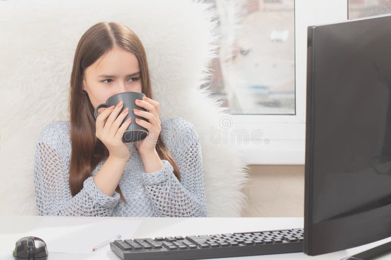 Young Woman Drinks Coffee in Front of Computer at Work in the Office ...