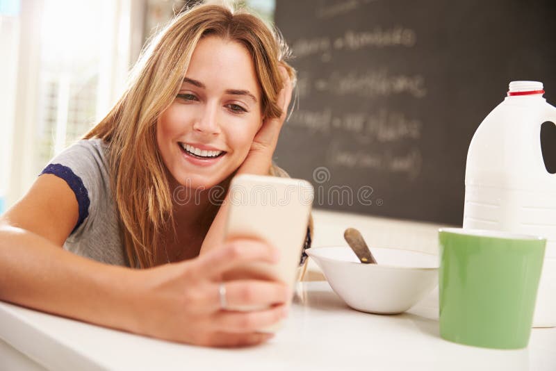 Young Woman Eating Breakfast Whilst Using Mobile Phone Stock Photo ...