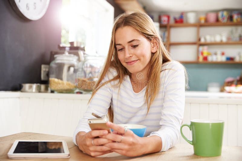 Young Woman Eating Breakfast Whilst Using Mobile Phone Stock Photo ...