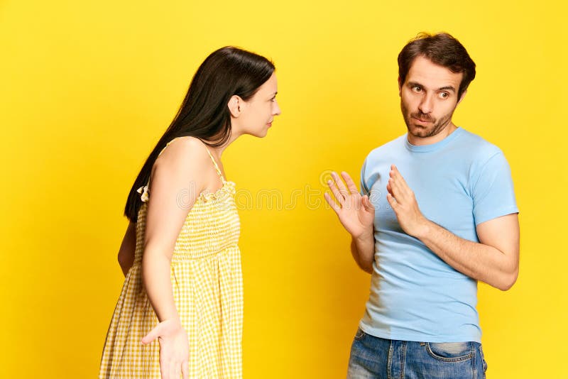 Young Woman Emotionally Talkin To Man, Asking Questions Against Yellow ... Young Woman Emotionally Talkin To Man, Asking Questions Against Yellow ...