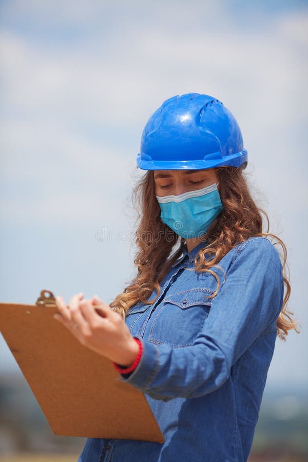 Young Woman Engineer Wearing Face Mask and Holding Clipboard with ...
