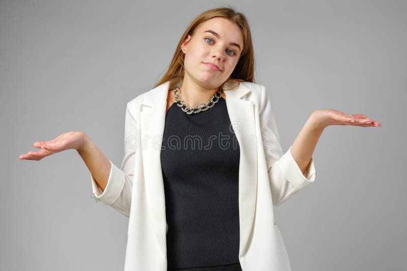 Young Woman Expressing Confusion with Hands Raised Against a Grey ...