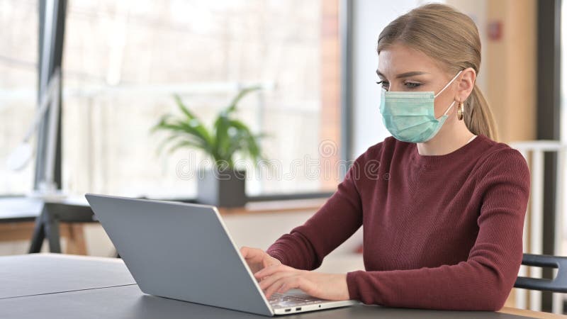 Young Woman with Face Mask Using Laptop in Office Stock Photo - Image ...