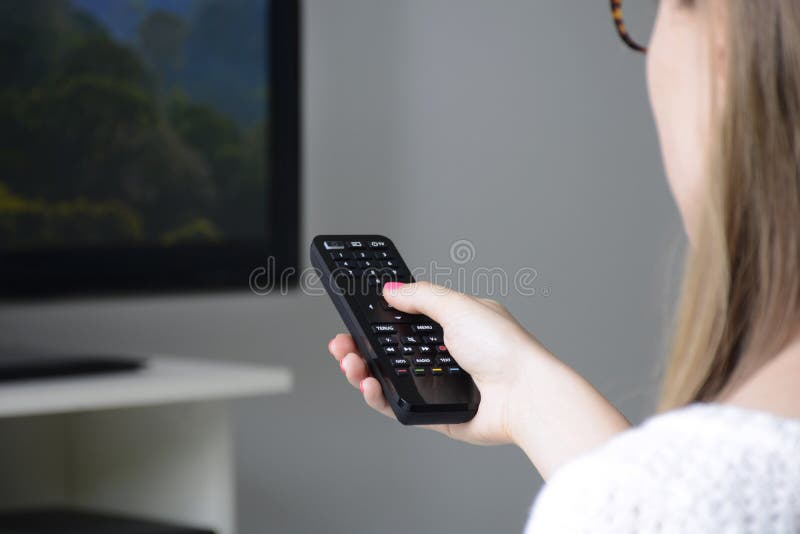 A Young Woman with Glasses Watching TV and Changing Channels with Tv ... A Young Woman with Glasses Watching TV and Changing Channels with Tv ...