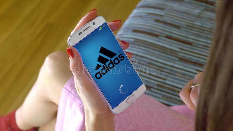 Young Woman Holding a Cell Phone with Loading Adidas Mobile App ...