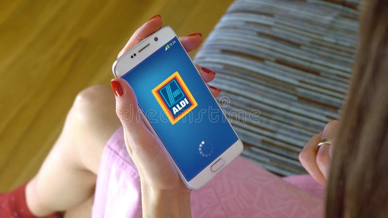 Young Woman Holding a Cell Phone with Loading ALDI Mobile App ...