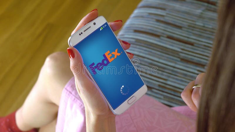 Young Woman Holding a Cell Phone with Loading Fedex Mobile App ...