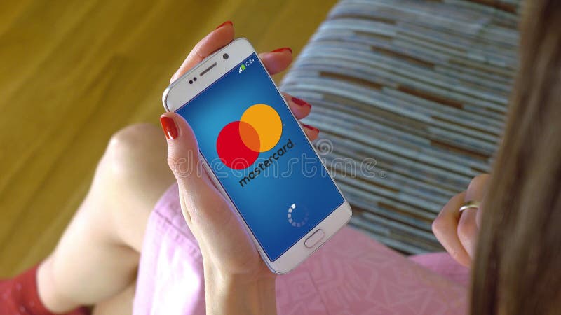 Young Woman Holding a Cell Phone with Loading Mastercard Mobile App ...