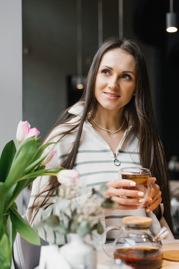 Young Woman Holds a Mug of Tea in Her Hands at a Table in a Cafe Stock ...