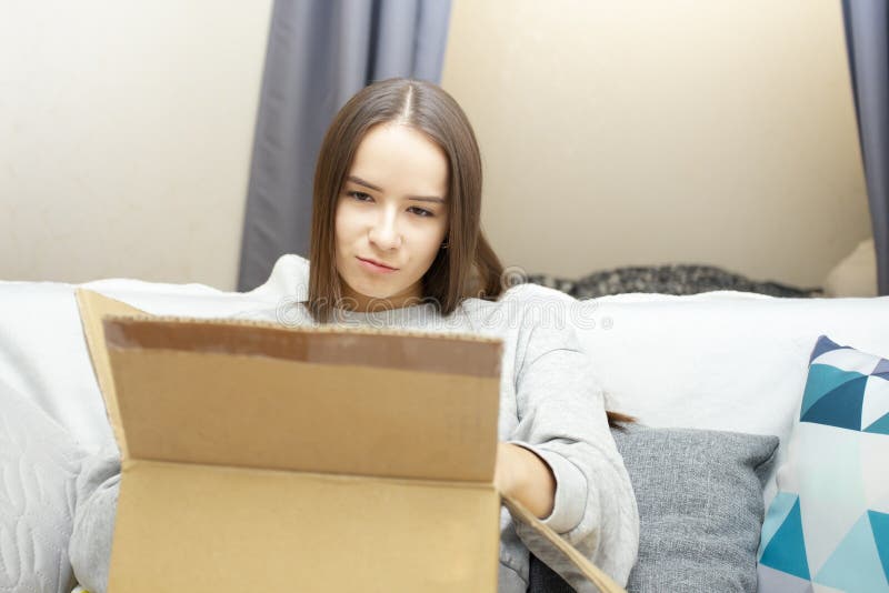Young Woman at Home Opens Mail Parcel, Upset by the Long Wait for the ...