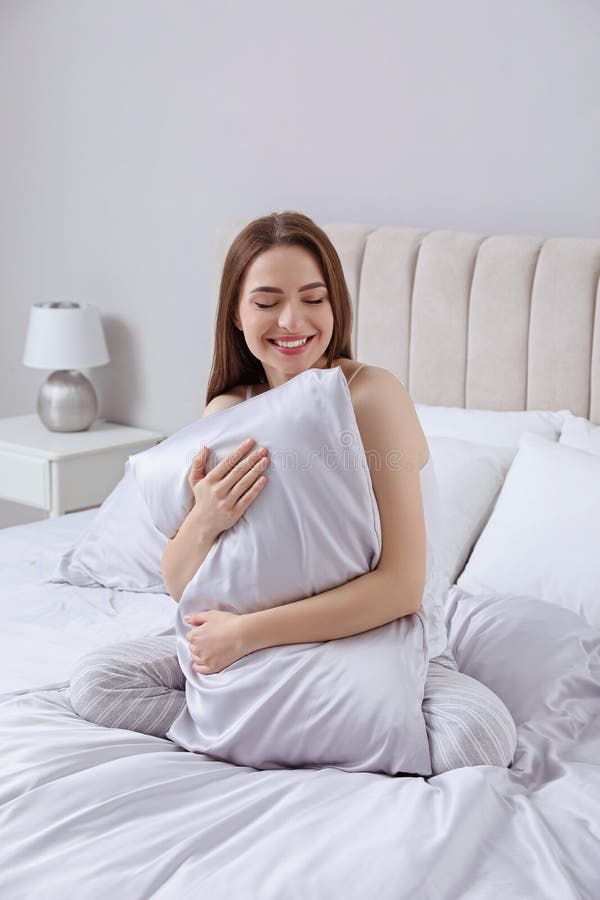 Young Woman Hugging Pillow on Bed with Silky Linens Stock Image - Image ...