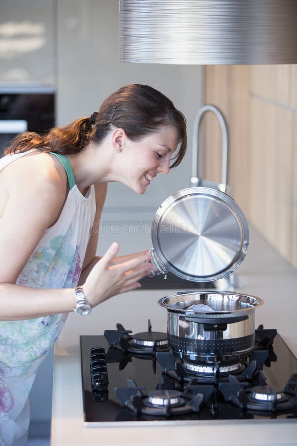 Young Woman Looking Inside of Pot in Kitchen Stock Photo - Image of ...