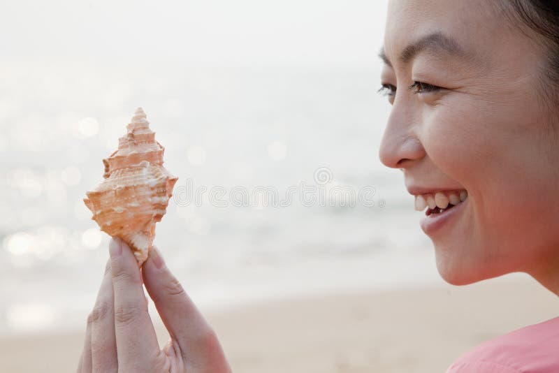 Young Woman Looking at Seashell Stock Photo - Image of 2529, focus ...