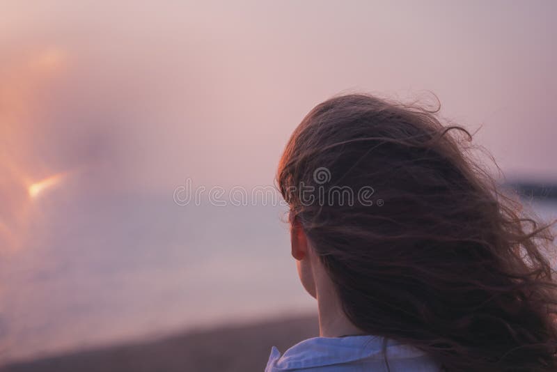 A Young Woman Looking at the Sunset at the Sea Standing with Her Back ...