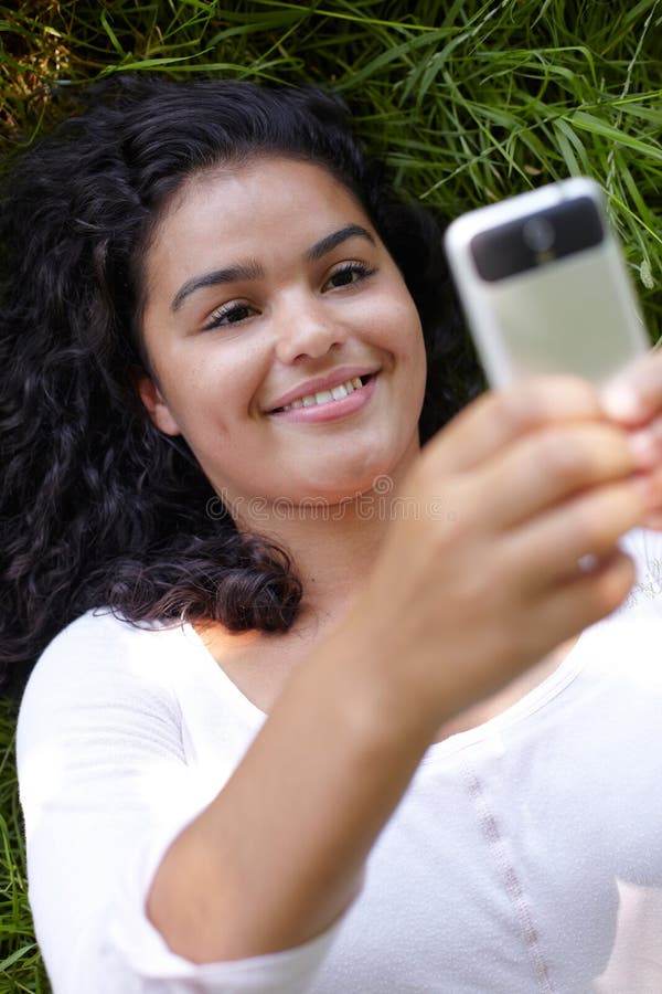 Young Woman Lying on Grass Sending Text Message Stock Photo - Image of ...