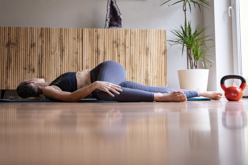 Young Woman Lying on the Mat on the Floor Making Stretching Exercise ...